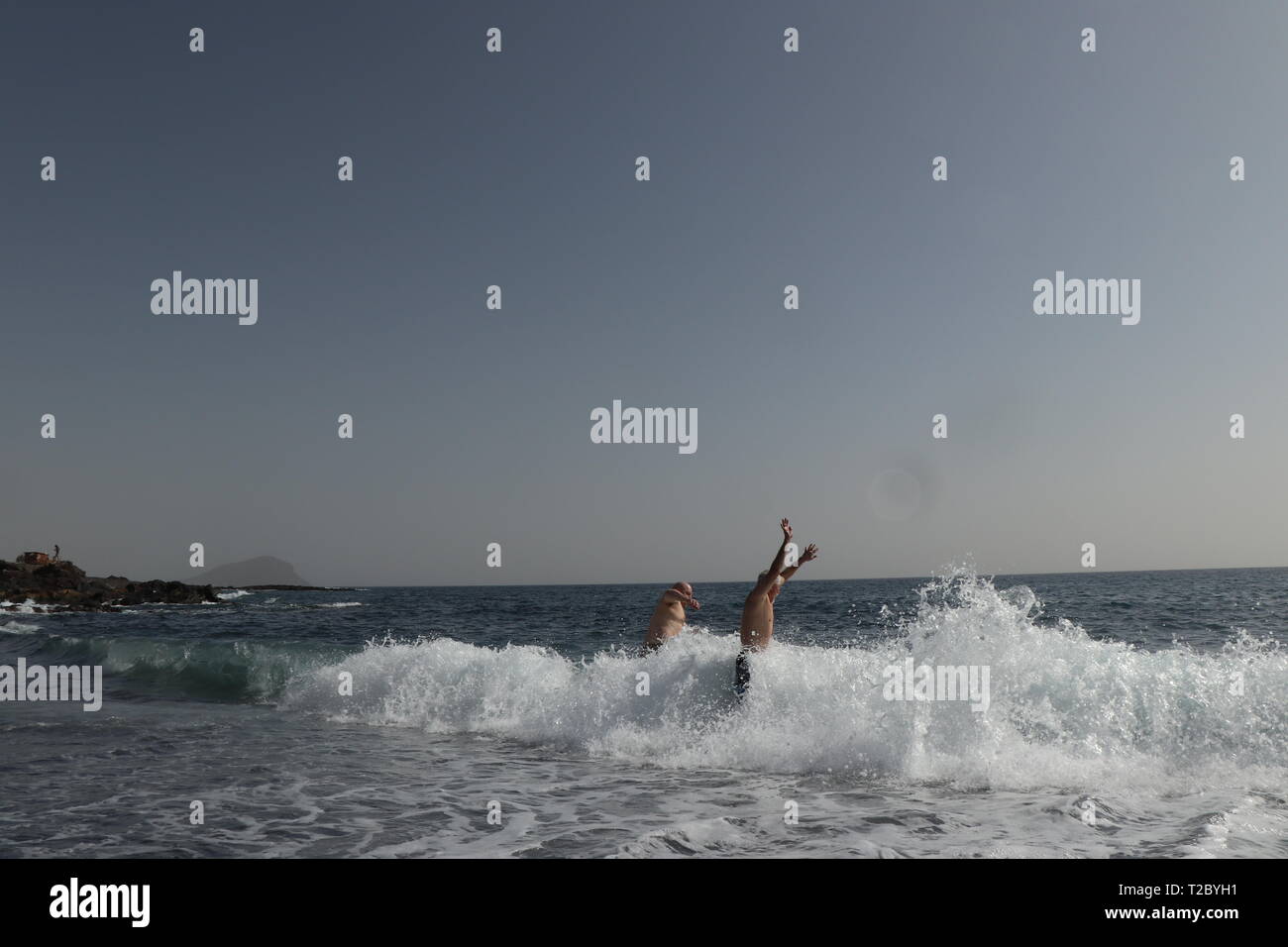 Men being splashed by wave on a beach in southern Tenerife, Spain Stock ...