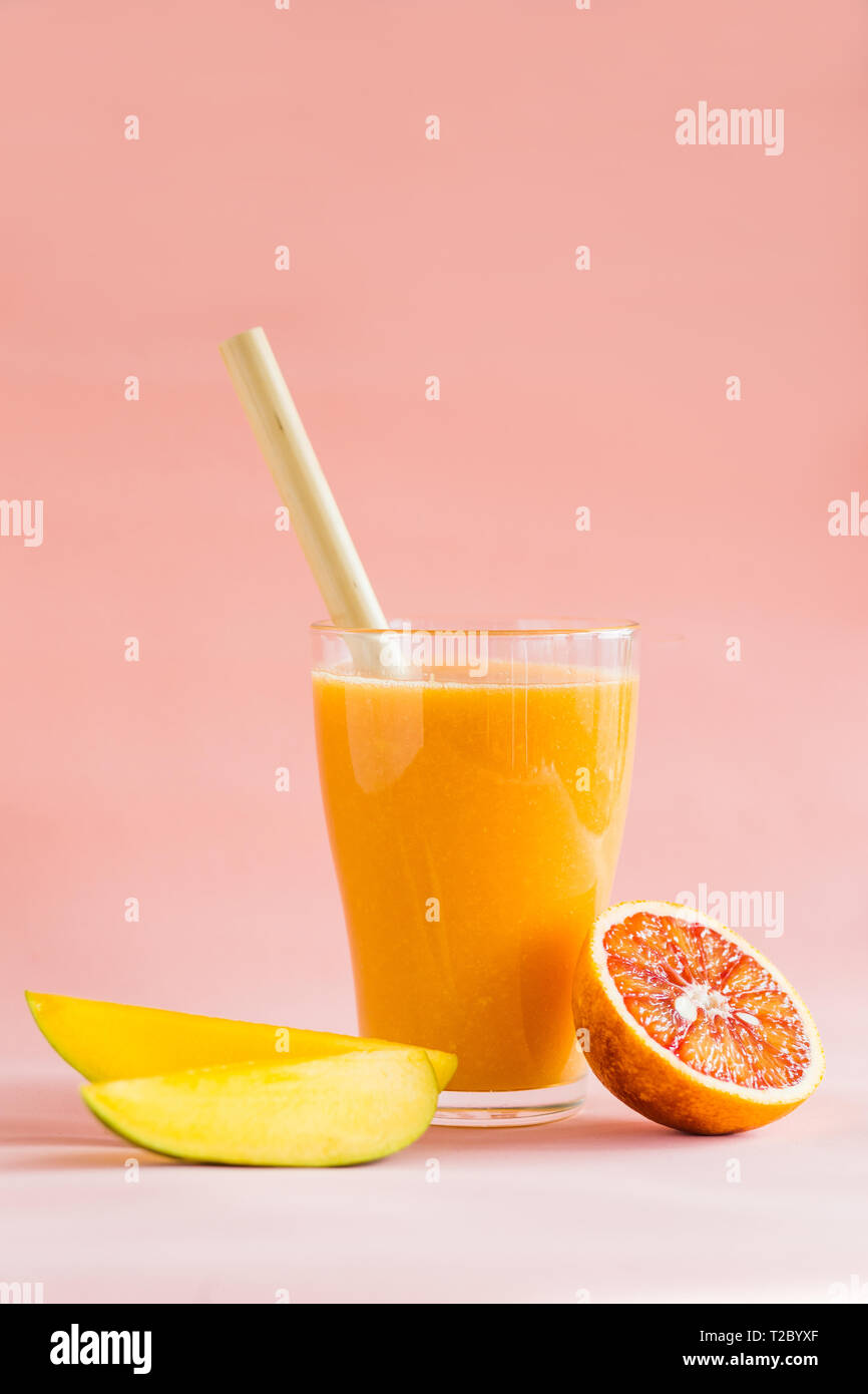 Glass of mango and orange juice on pink background. Refreshments and ...
