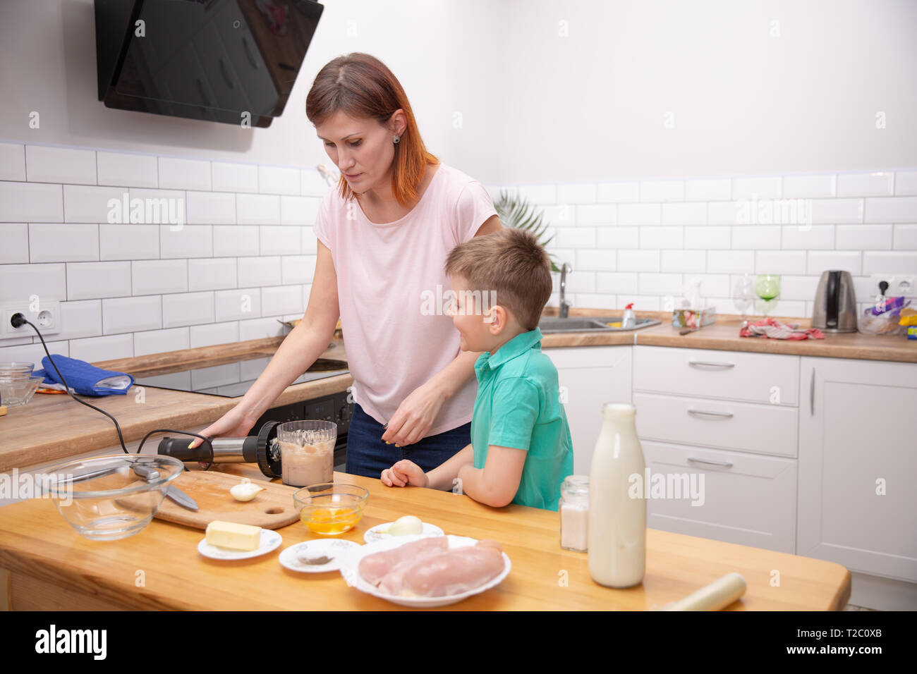 Little boy helping his mother with the cooking in the kitchen. Little ...