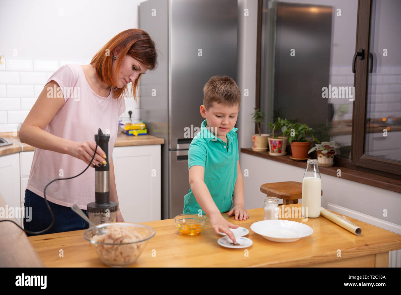 Little boy helping his mother with the cooking in the kitchen. Little ...