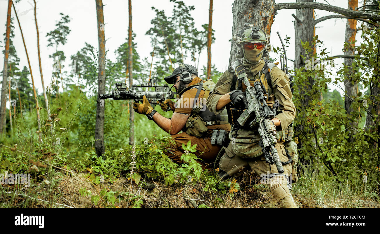 Airsoft men with guns stand back to back. Soldiers stand on hill and on ...