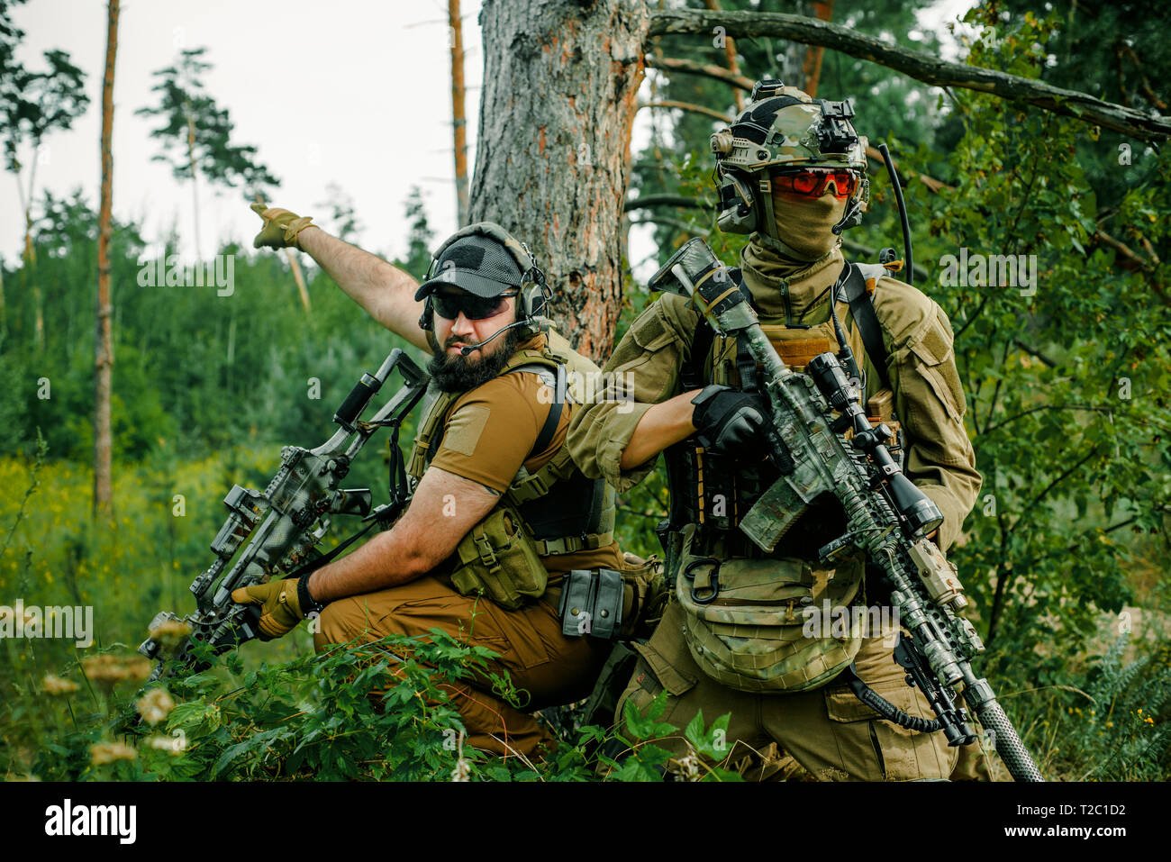 Airsoft men with guns stand back to back. Soldiers stand on hill and on ...