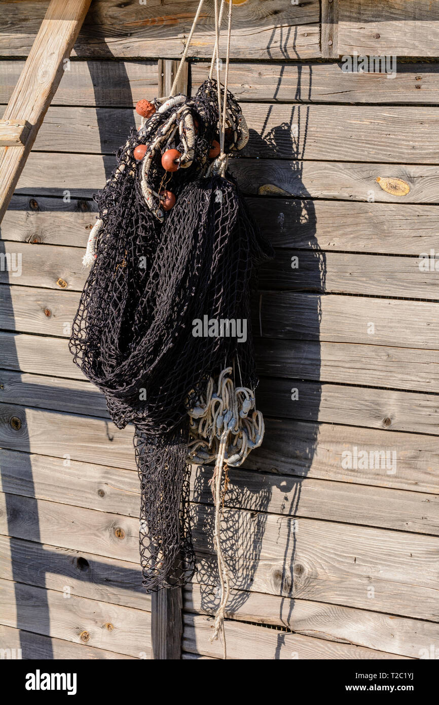 Detail of black fishing net with floats hanging on the old wooden boat ...