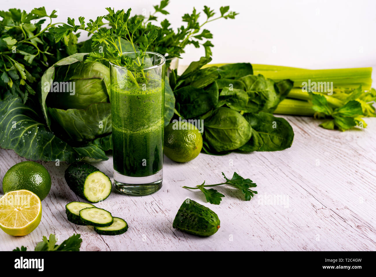 Green vegetable detox smoothie in glass at wooden white background ...
