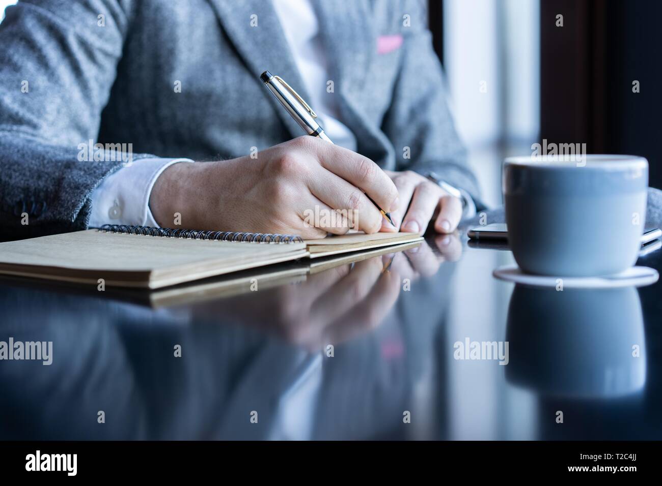 Man hand with pen writing on notebook on table. Man working at coffee ...