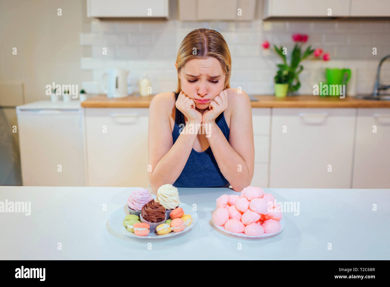 Diet struggle. Young sad woman in blue T-shirt chooses between fresh ...