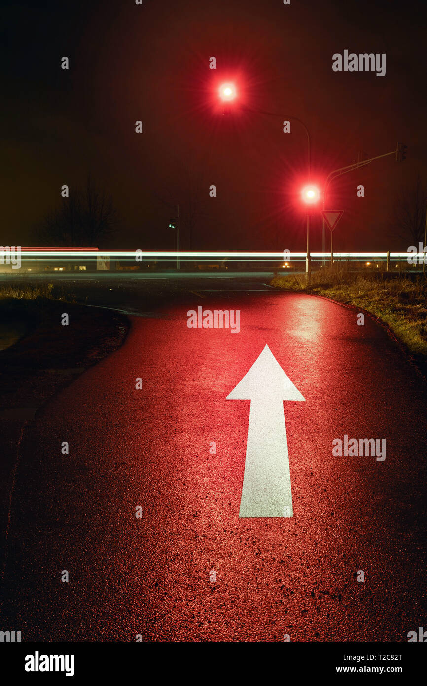 Traffic light showing red light in wet night with white arrow on ...