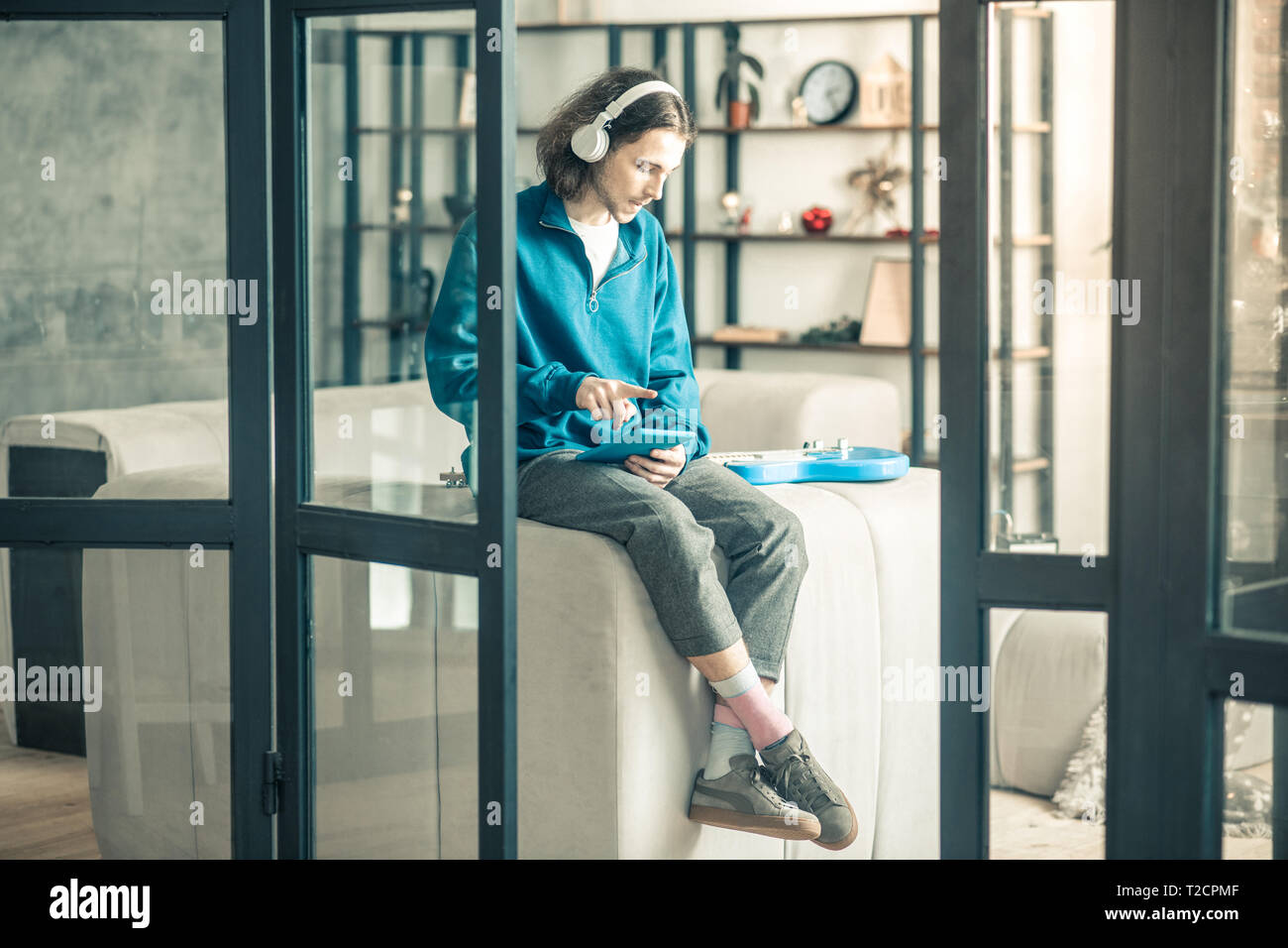 Attentive long-haired man carrying tablet and observing information ...