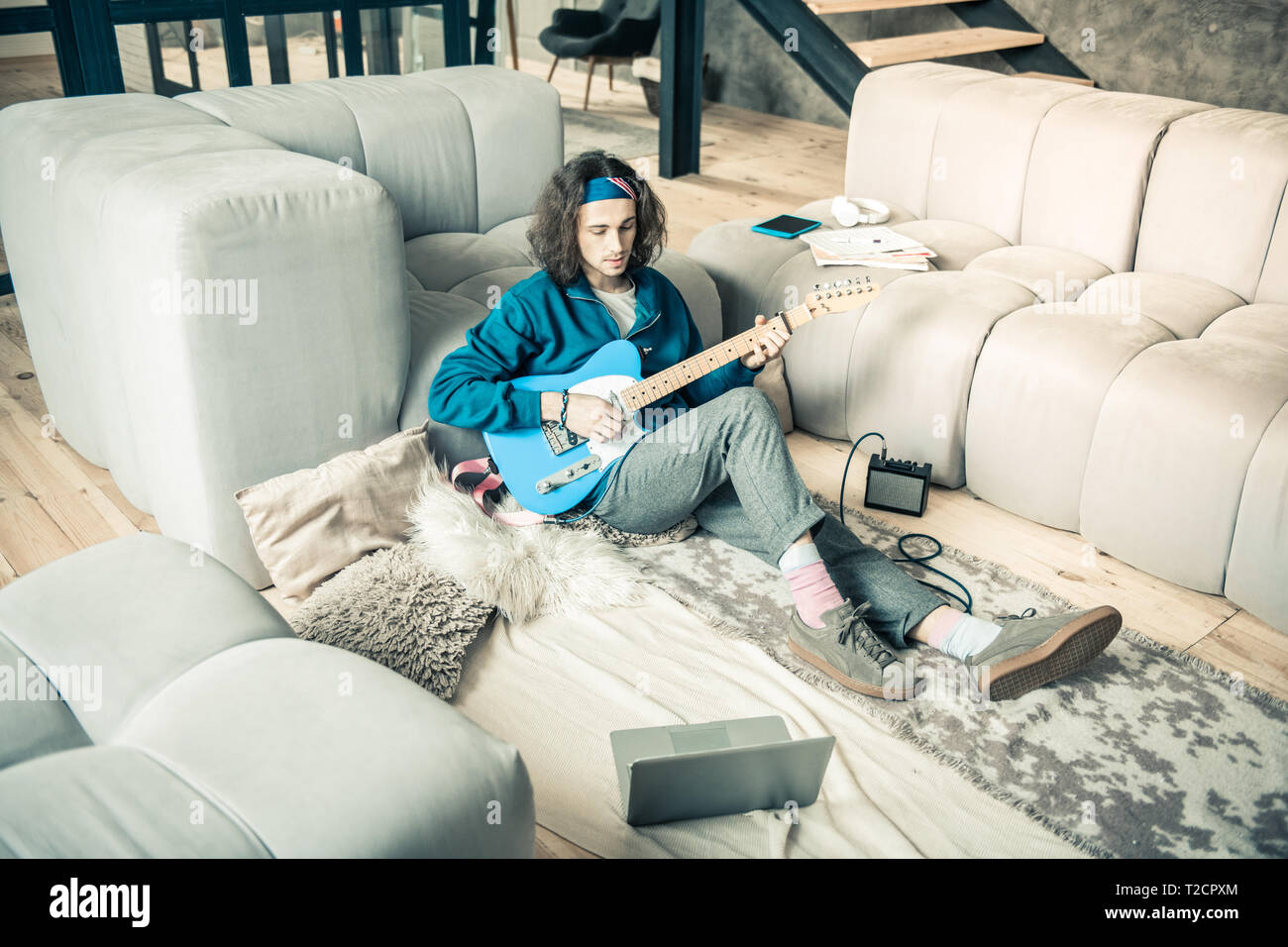 Calm young performer sitting on the floor and leaning new compositions ...