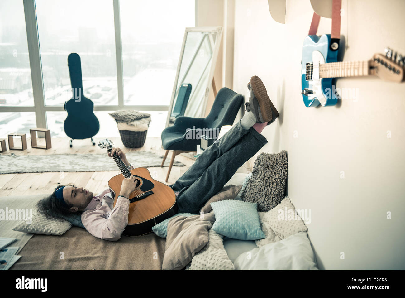 Melancholic young artist leaning on clear wall with his legs Stock ...