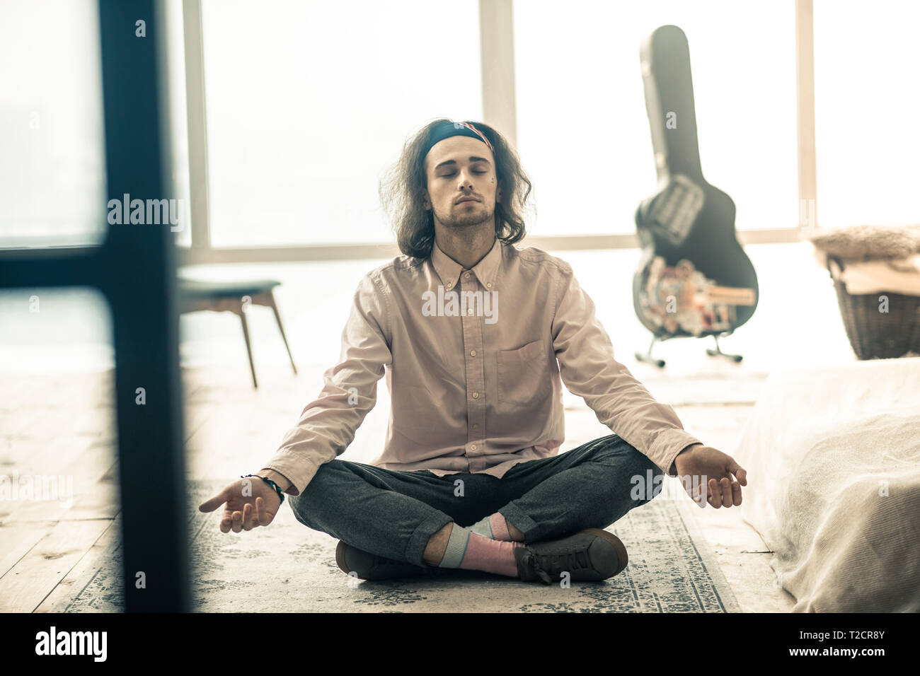 Peaceful long-haired man sitting in lotus posture in the middle of the ...