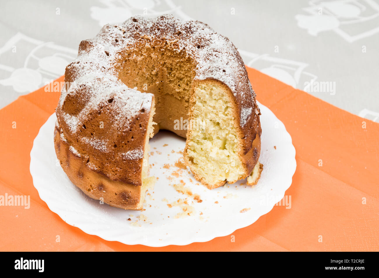 Homemade ring cake dusted with icing sugar on white plate Stock Photo ...