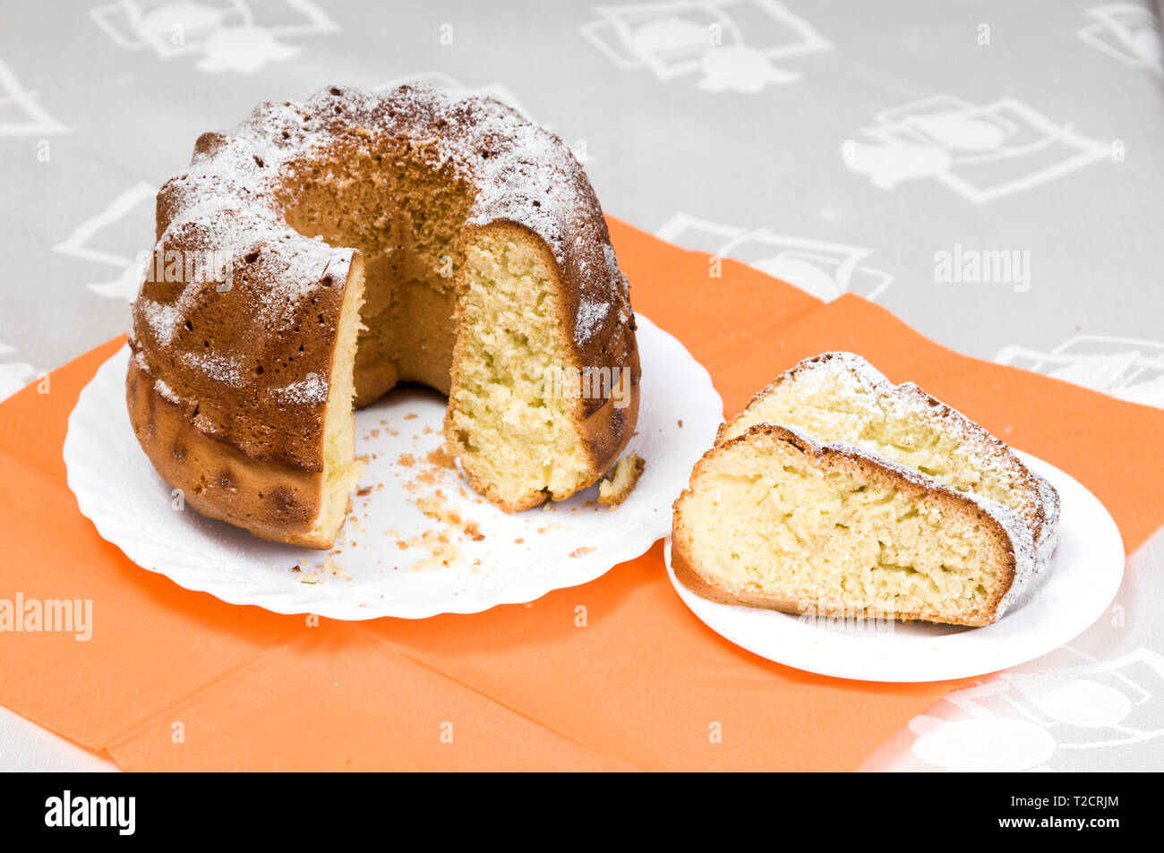 Homemade ring cake dusted with icing sugar on white plate Stock Photo ...