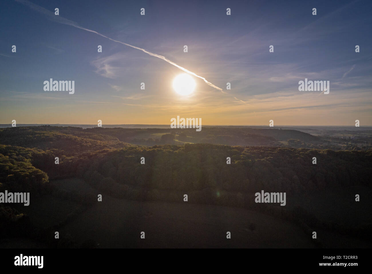 Sun setting over forrest hills in the Eifel region in West Germany ...