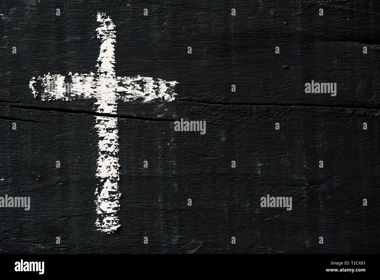 closeup of a christian cross painted with chalk on a rustic dark gray ...