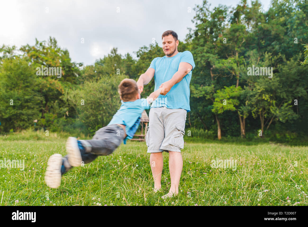 man spinning boy at green field. playing around. fun time Stock Photo ...