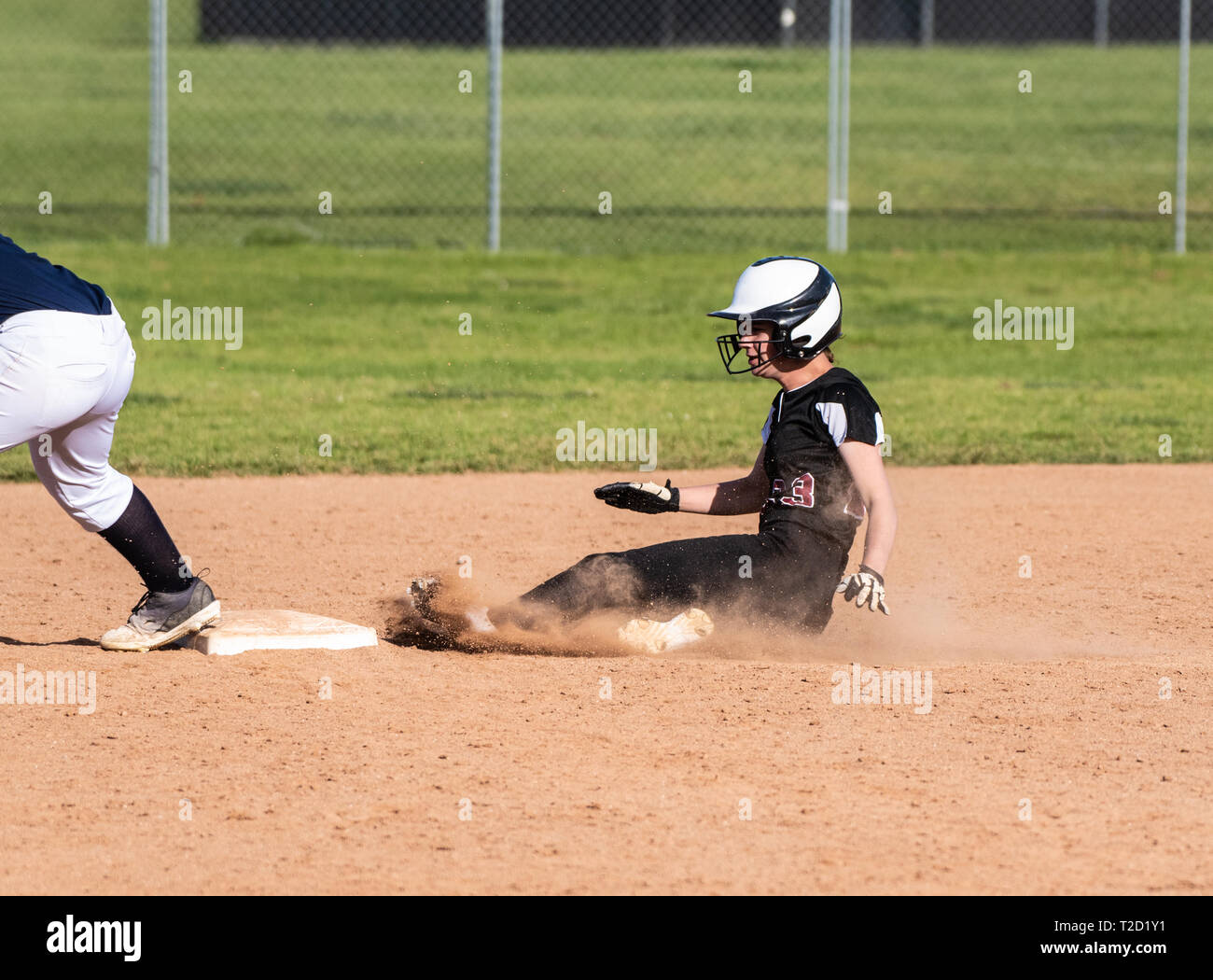 Skilled teenage softball player sliding safely into second base in a ...