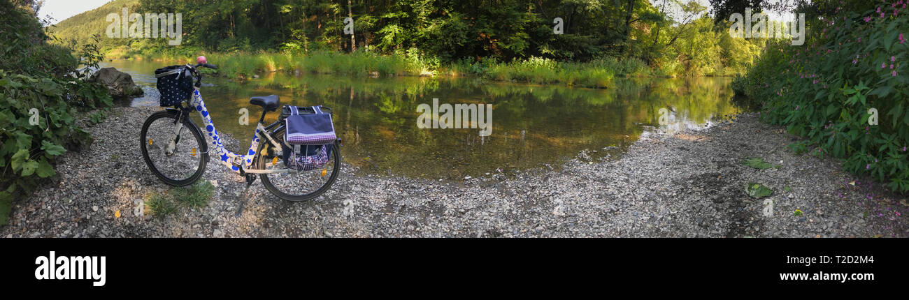 A colorful e bike parked in green landscape with bushes and trees. Bank ...