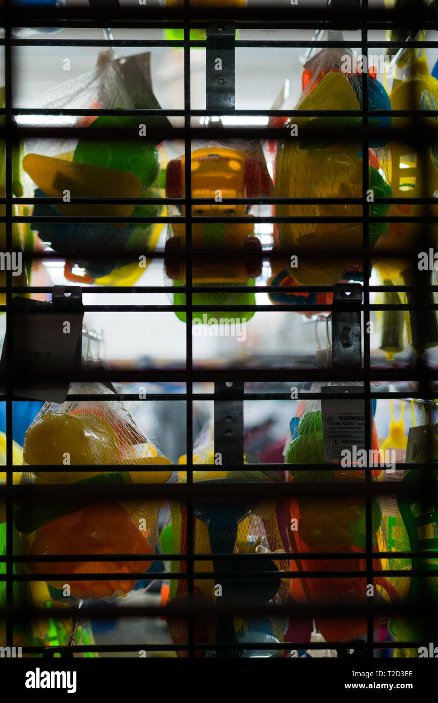 Colorful plastic toys hanging in a window display behind the closed ...