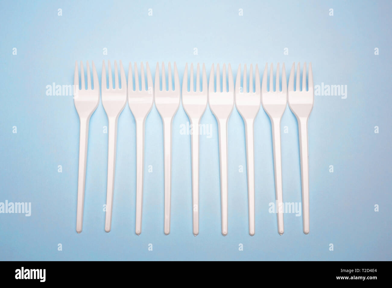 Single-use plastic products: plastic cutlery on bright blue background ...