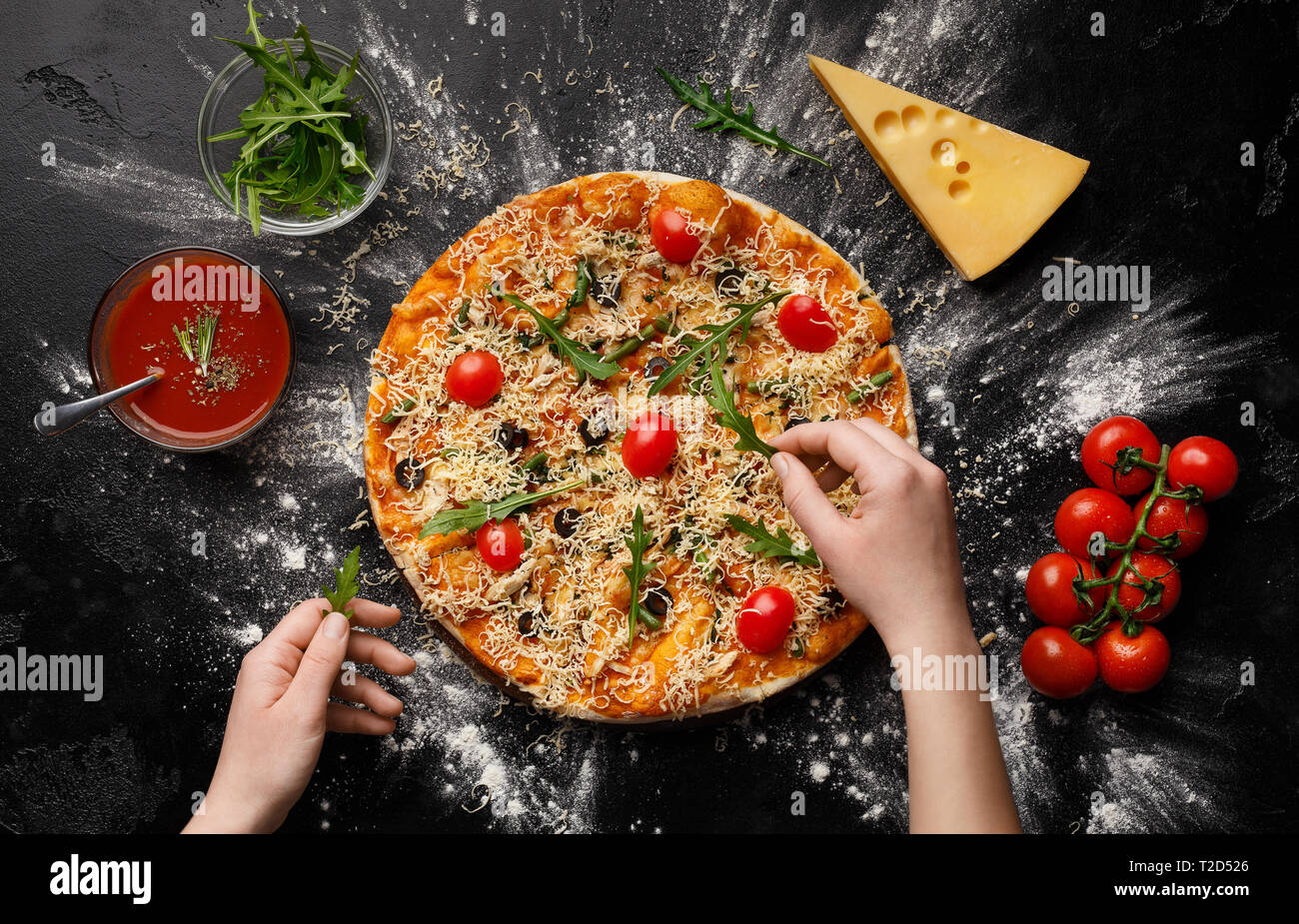 Chef decorating pizza with rocket salad and cherry tomatoes, top view ...