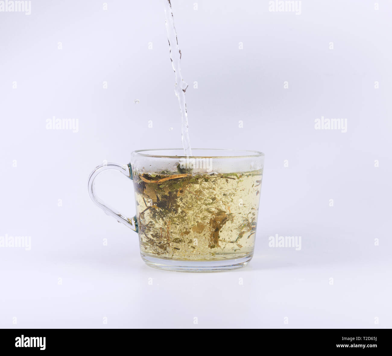 pouring hot water to the glass cup with tea, isolated on white ...