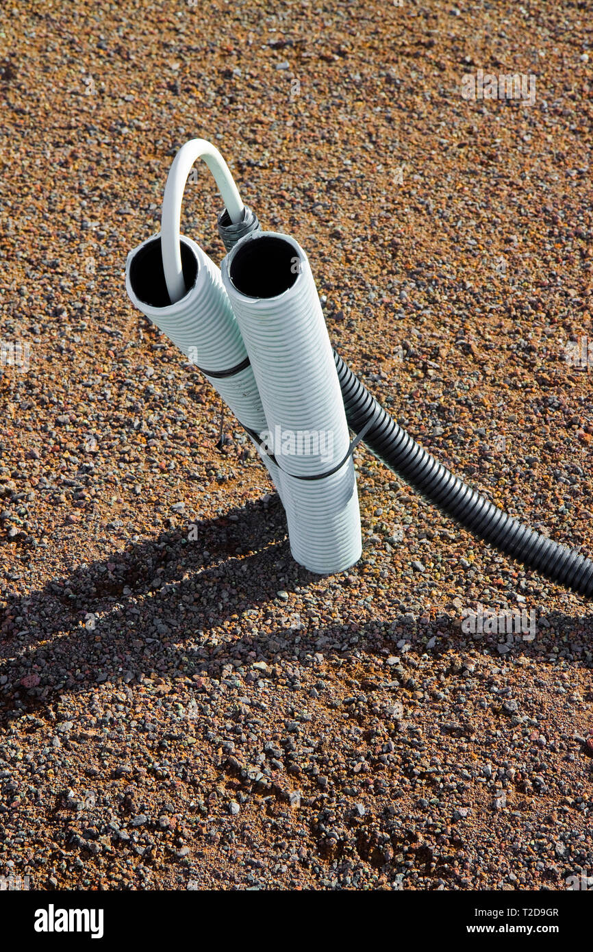 Corrugated pipe with cable coming out from the ground Stock Photo - Alamy