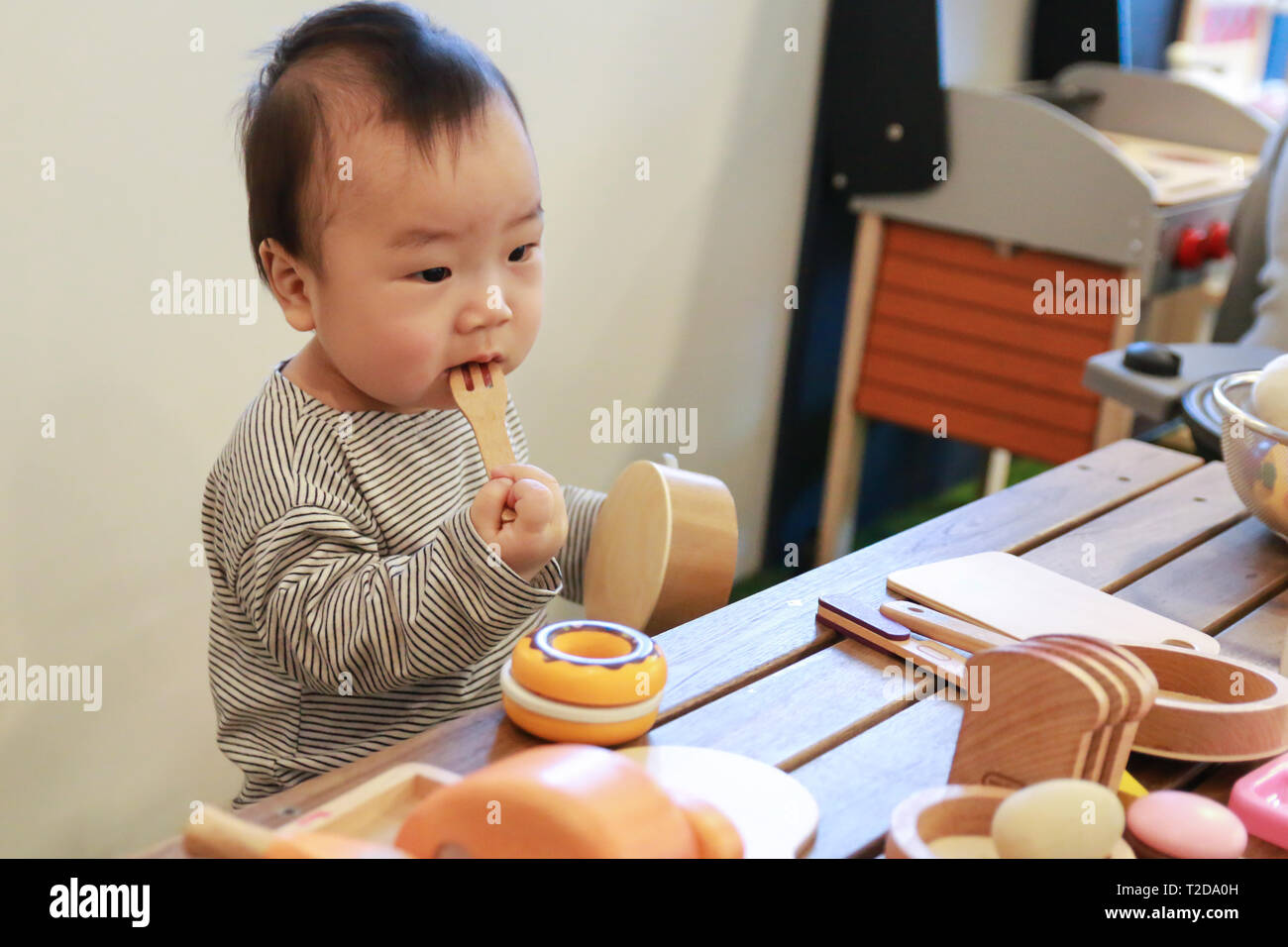Asian baby playing with camping gear toy tools on the wooden table in ...