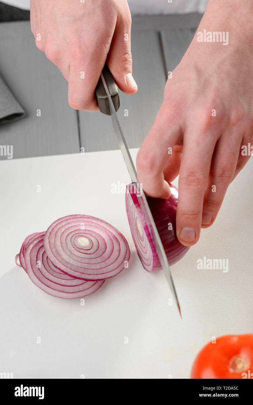 Man slicing a red onion into rings. Ingredient for savory flavor ...