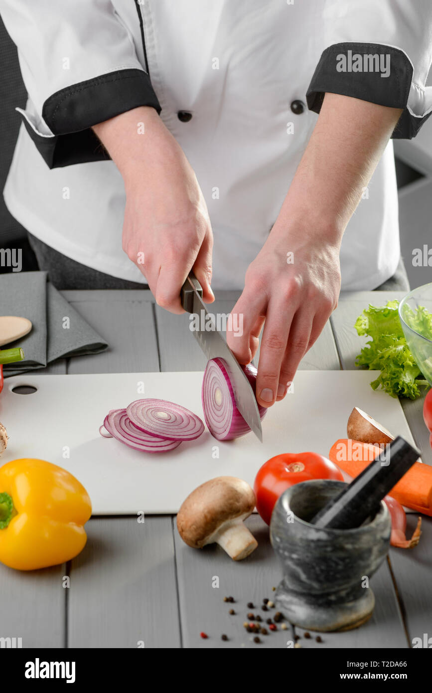Chef cutting a red onion into rings, demonstrating perfect knife skills ...