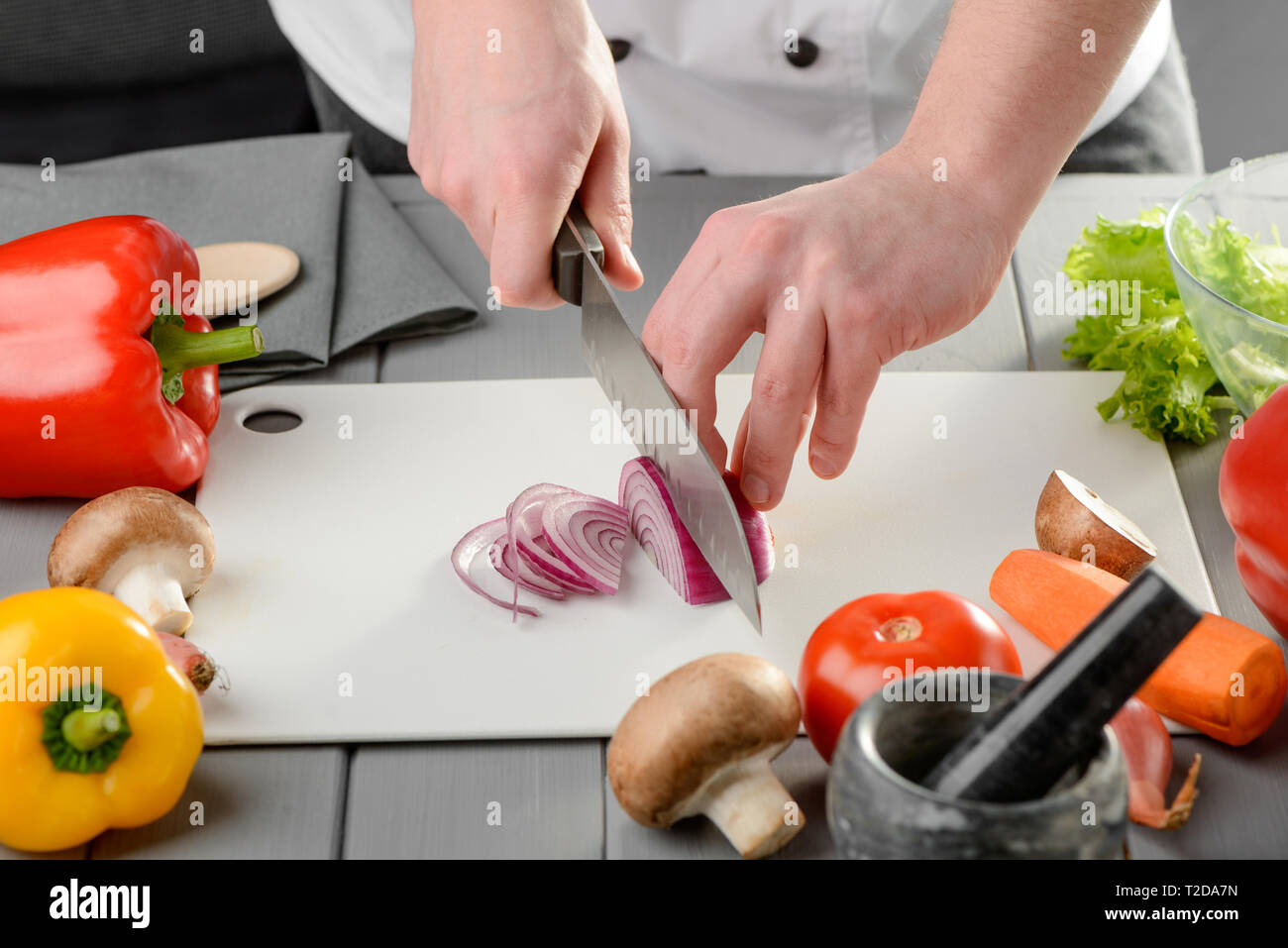 Chef slicing a red onion into rings on a cutting board. Fresh ...