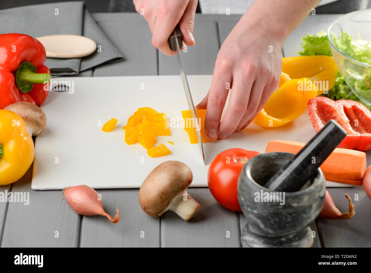 Cooking a healthy meal with vegetables. Man dicing a yellow bell pepper ...