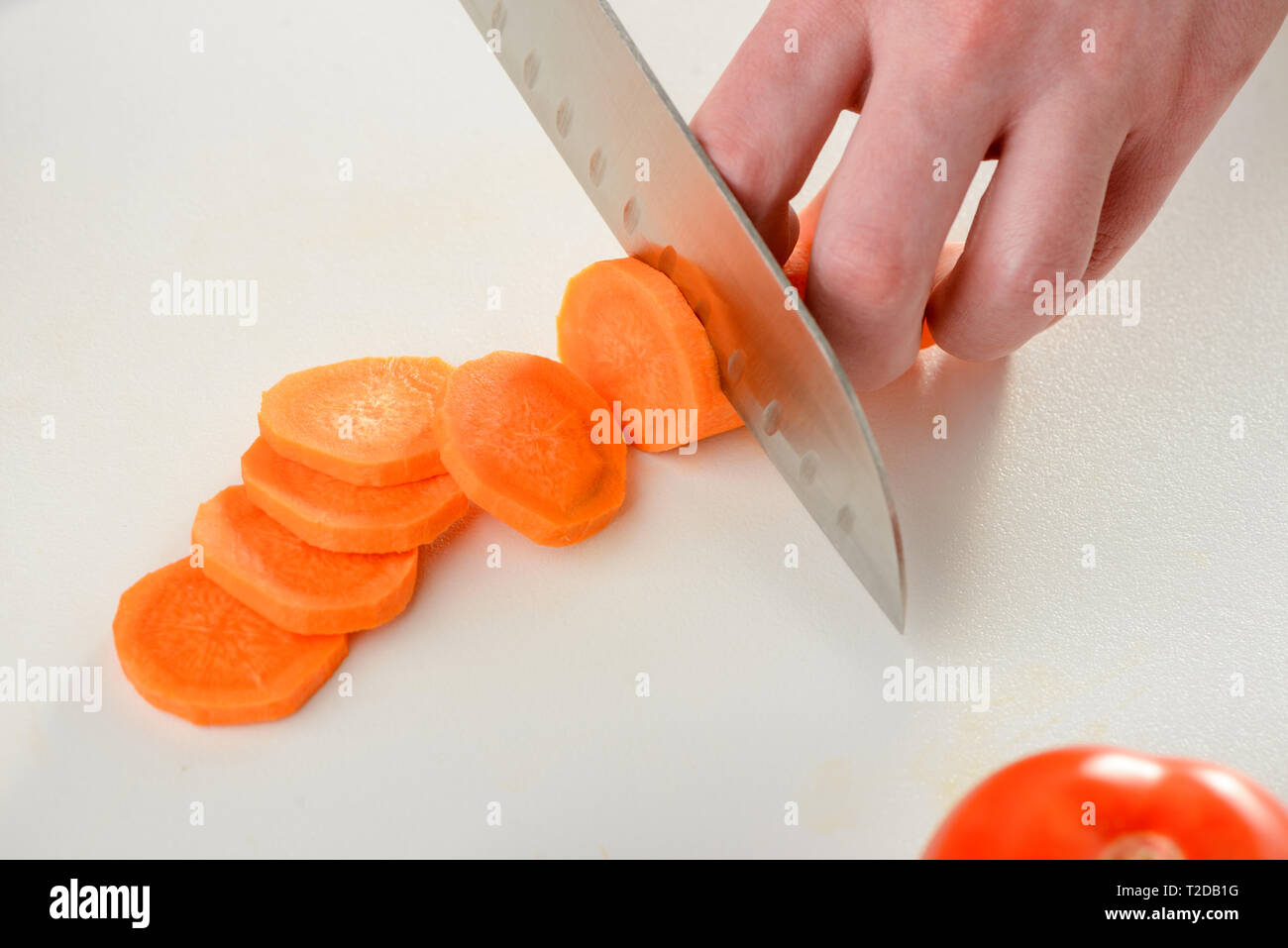 Chef cutting a carrot into circle slices with a santoku knife on a ...