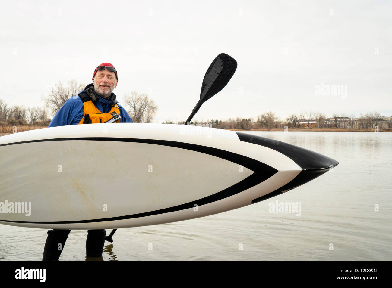 Happy and smiling senior paddler (mid 60s) with his stand up ...