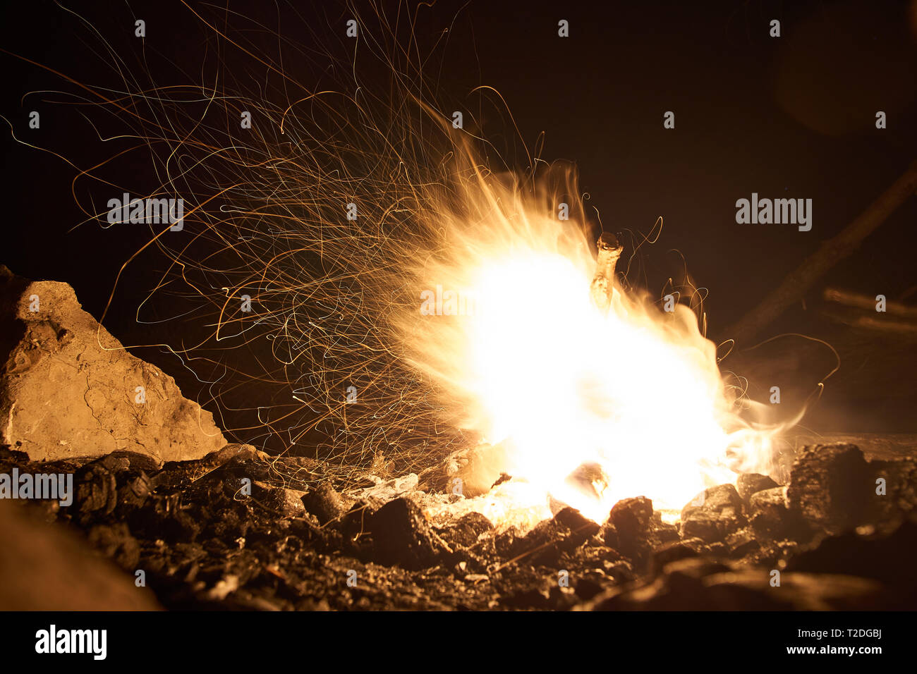 A campfire burns brightly in an outdoor, stone fire pit on a cold early ...