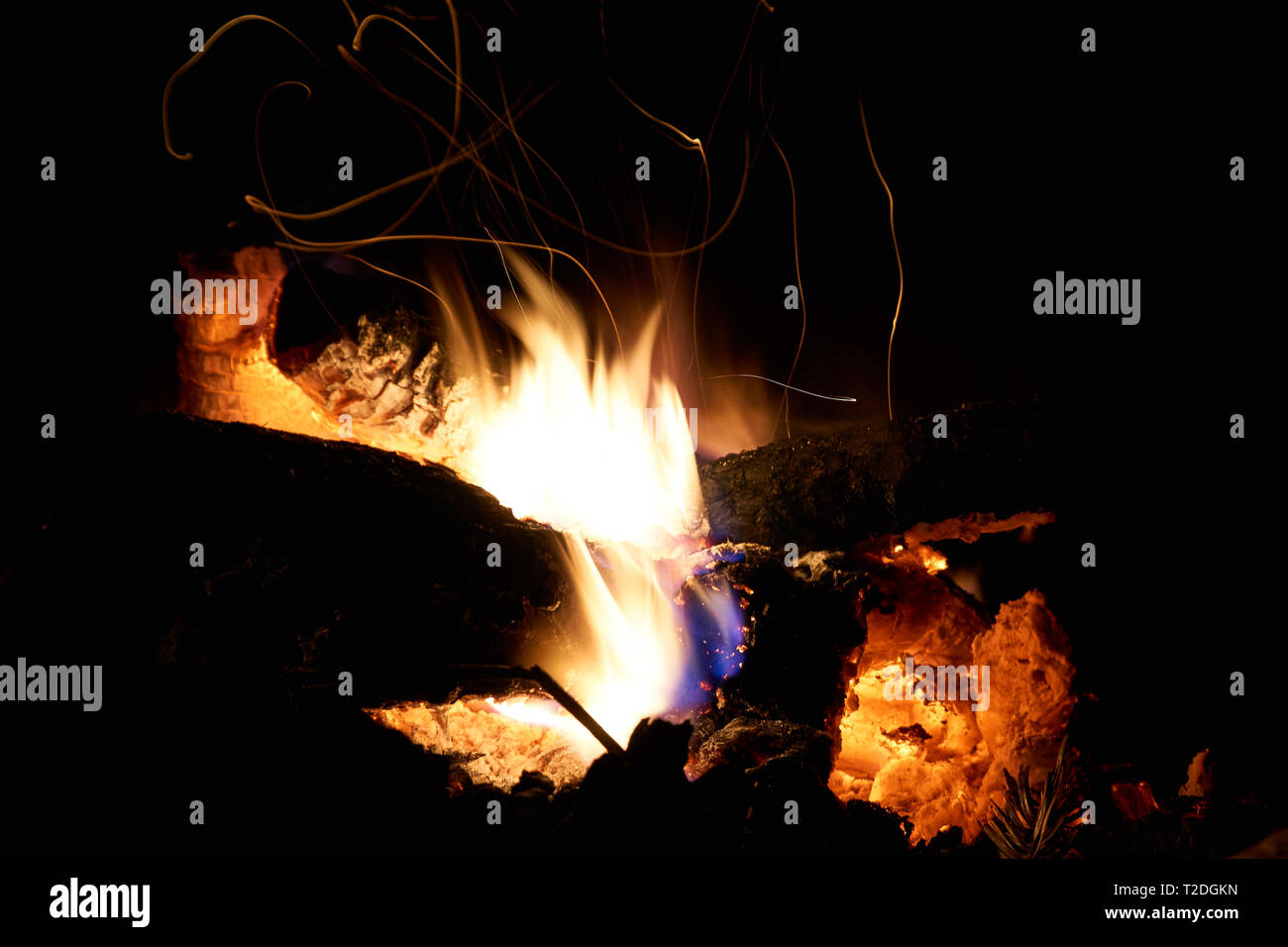 A campfire burns brightly in an outdoor, stone fire pit on a cold early ...