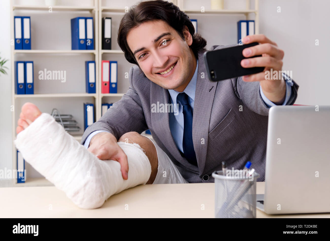 Leg injured employee working in the office Stock Photo - Alamy