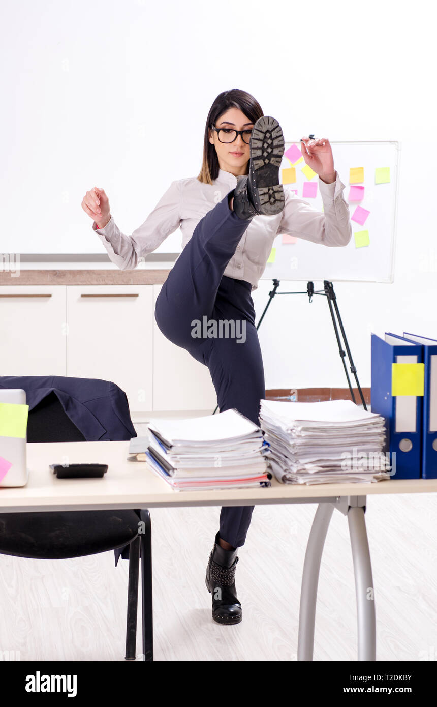 Young female employee doing exercises at workplace Stock Photo - Alamy