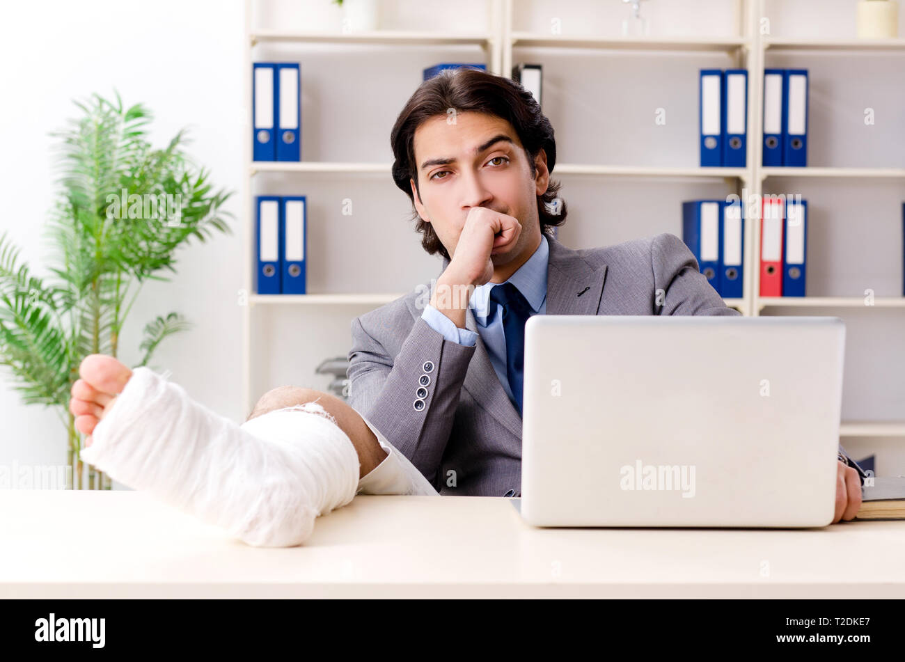 Leg injured employee working in the office Stock Photo - Alamy