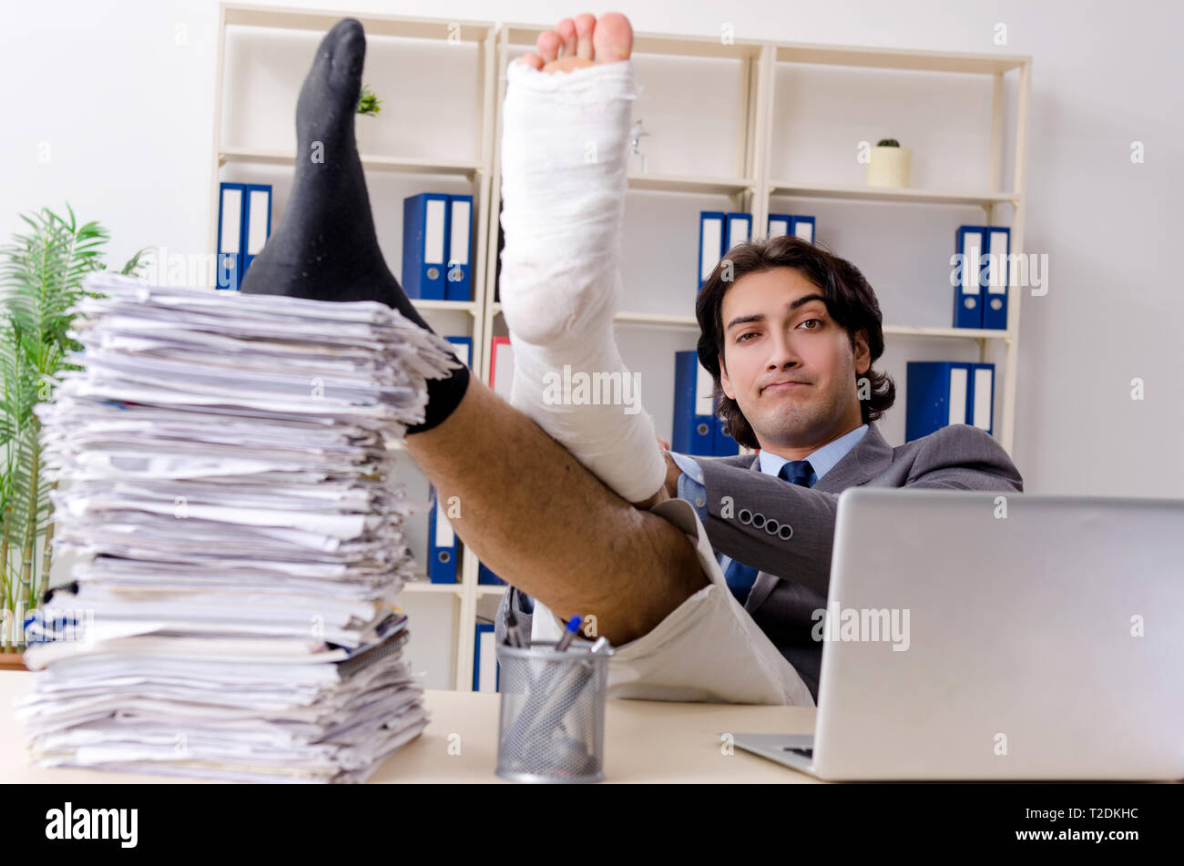 Leg injured employee working in the office Stock Photo - Alamy