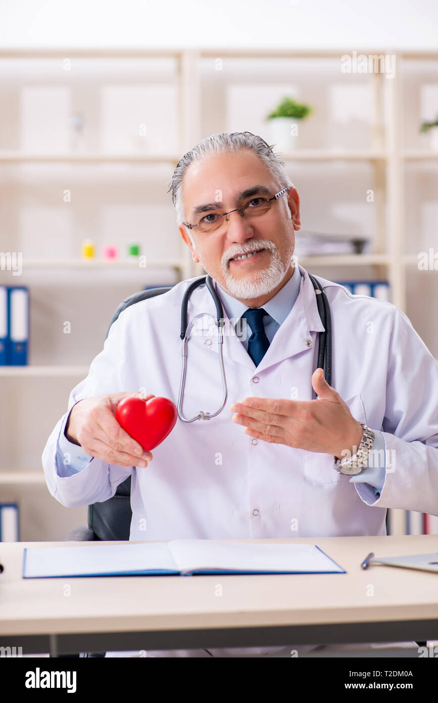 Aged male doctor cardiologist with heart model Stock Photo - Alamy