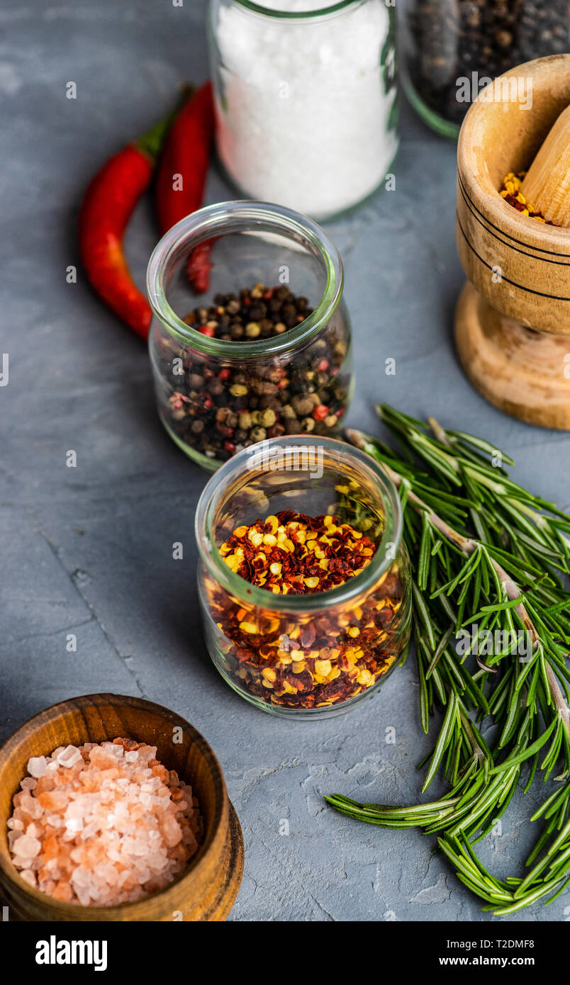 Organic spices like pepper, rosemary, different types of salt on rustic ...