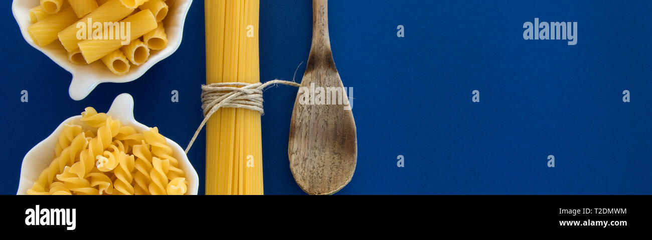 Different Italian pasta products on blue background, space for menu or ...