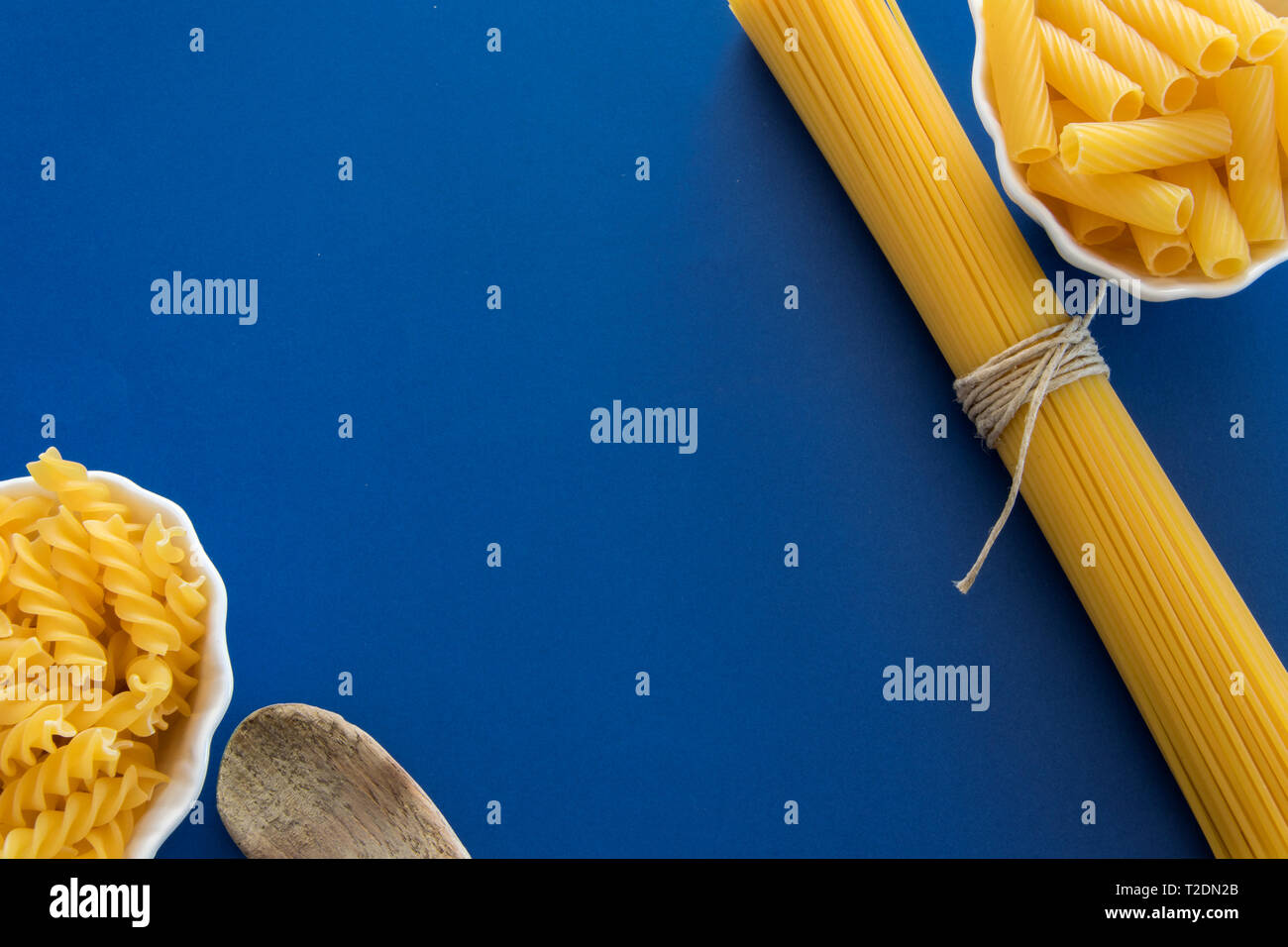 Different Italian pasta products on blue background, space for menu or ...
