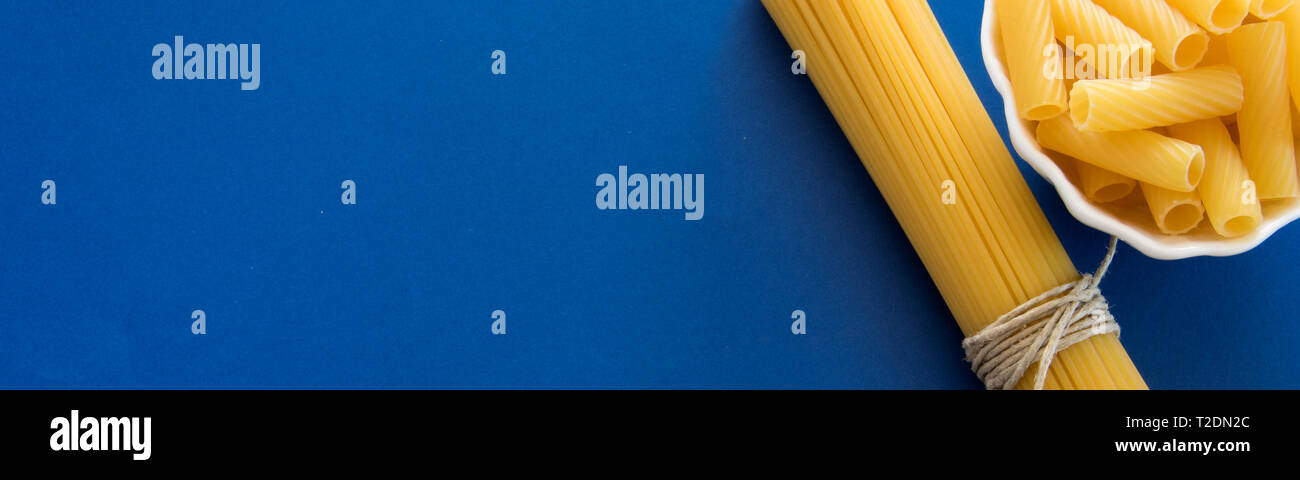 Different Italian pasta products on blue background, space for menu or ...