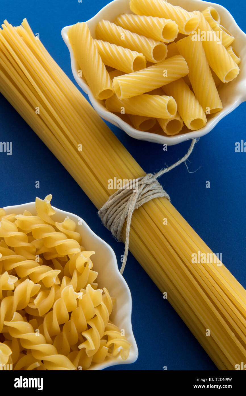 Different Italian pasta products on blue background Stock Photo - Alamy