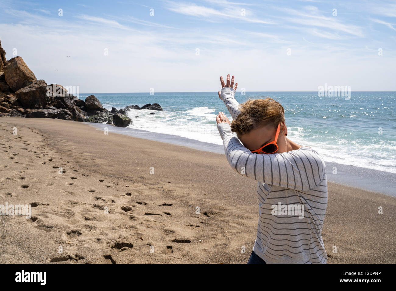 Adult caucasion woman does a dabbing dance move while on the beach ...
