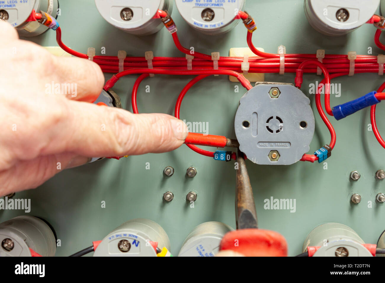 Electrician using long nose pliers and screwdriver to connect wiring to ...