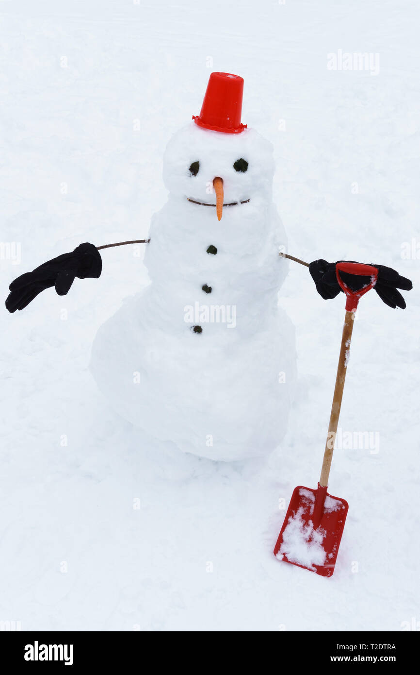 Snowman in red bucket hat and black gloves with orange nose, holding a ...