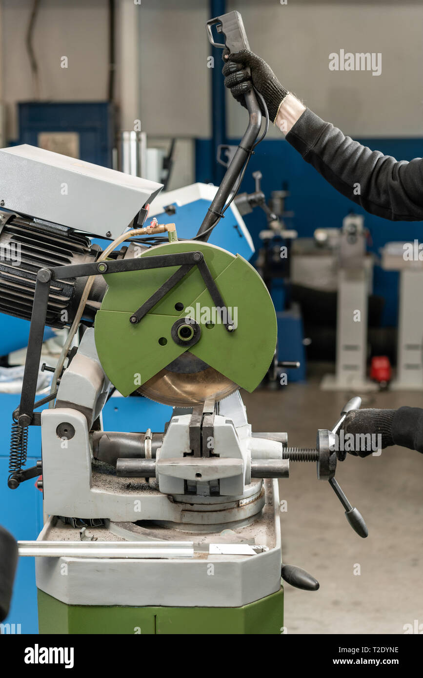 worker cuts a piece of material with a circular saw machine. Industrial ...